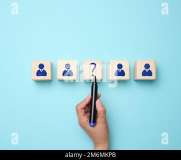 Wooden figures of men and a woman's hand drew a question mark with a ...