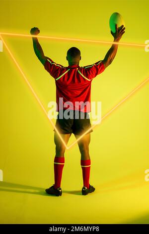 Rear view of african american rugby player with arms raised standing by ...