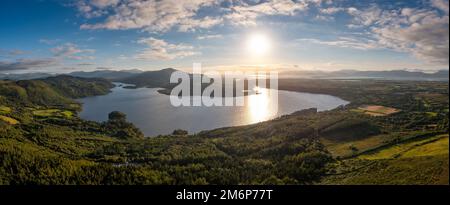 An aerial panorama of Caragh Lake in County Kerry with the sun setting ...