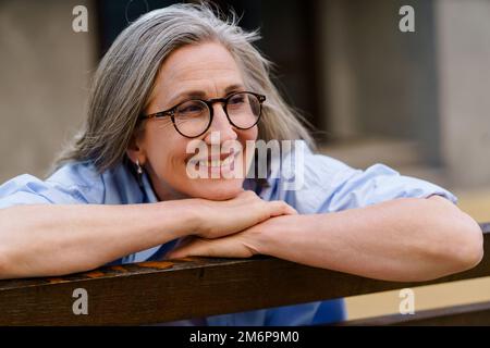 Leaned on the bench happy mature grey hair woman smiling sitting ...
