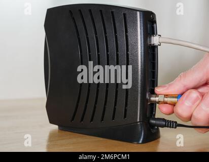 Connecting coaxial cable to cable modem. Man installing high speed ...