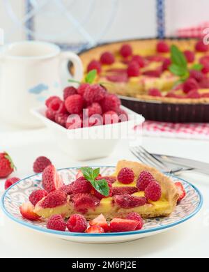 Round quiche with red strawberries and raspberries on a white table ...
