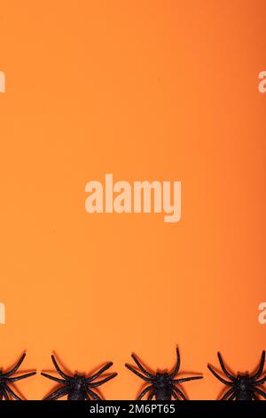 Close up of multiple spider toys with copy space against orange ...