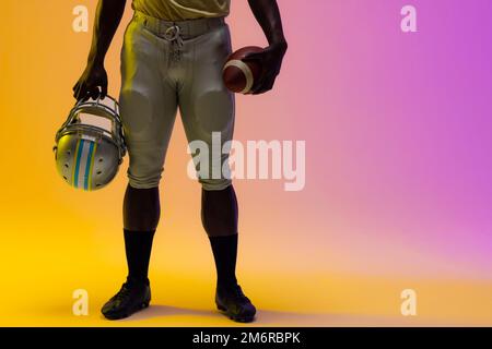 Midsection of african american male american football player with neon ...