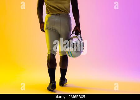 Midsection of african american male american football player with neon ...