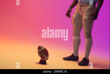 Midsection of african american male american football player with neon ...