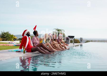 Happy diverse friends with santa hats embracing in garden at christmas ...