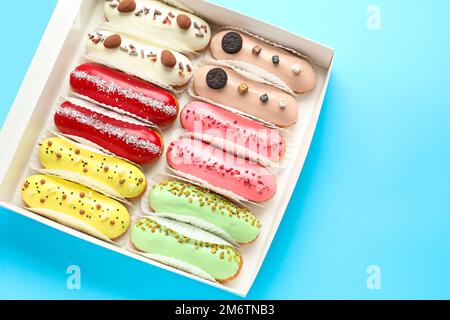 Box with various glazed eclairs on blue background Stock Photo - Alamy