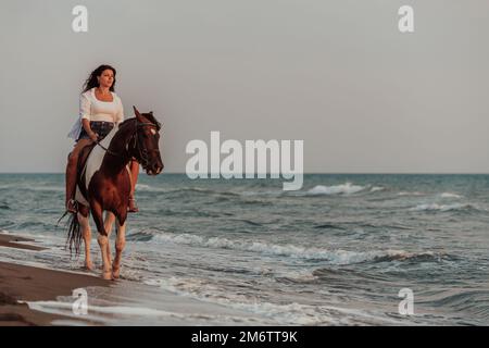Woman in summer clothes enjoys riding a horse on a beautiful sandy ...