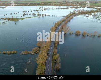 A car drives along the road as the Welney wash fills with floodwater as ...