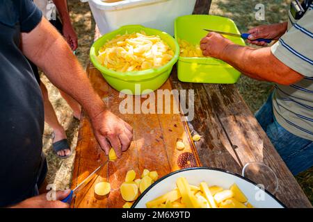 Teamwork of two farmer cookers cut potatoes using knives into slices on ...