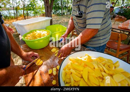 Teamwork of two farmer cookers cut potatoes using knives into slices on ...