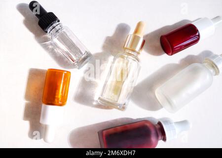 Serum with collagen and peptides in colorful glass bottles on light ...
