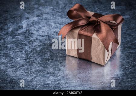 Giftbox with brown ribbon on scratched metallic background holidays ...