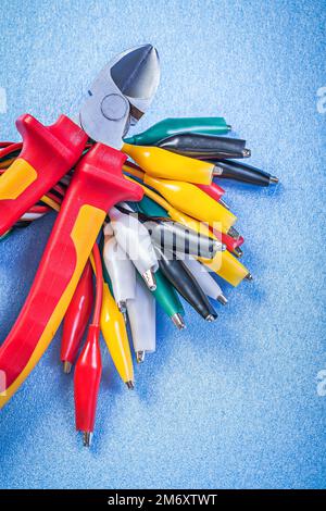 Set of multicolored cable crocodiles cutting pliers on blue background ...