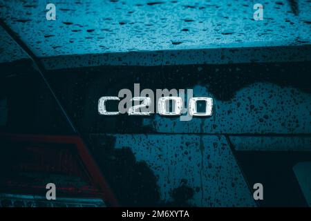 A closeup of the Mercedes c200 logo and emblem on the wet, blue trunk ...