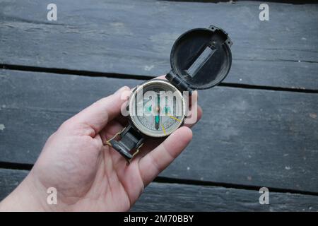 Hand holding traditional magnetic compass, vintage retro style ...