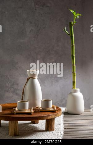 Japanese sake still life with a sprig of bamboo, light linen background ...