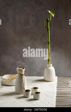 Japanese sake still life with a sprig of bamboo, light linen background ...