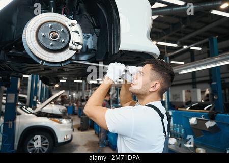 Mechanic removing old wheel from car in tire fitting Stock Photo - Alamy