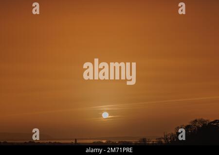 The setting sun disappearing behind some cloud cover Stock Photo - Alamy