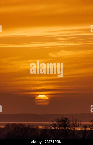 The setting sun disappearing behind some cloud cover Stock Photo - Alamy