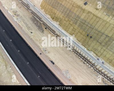 Mountain road constraction. Workers reinforce the slope over the new ...