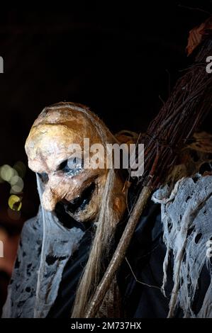 Witch with a broom and a monster face on a dark halloween horror night ...