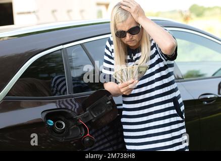 Desperate woman hold cash dollar bills in to car with an open tank ...