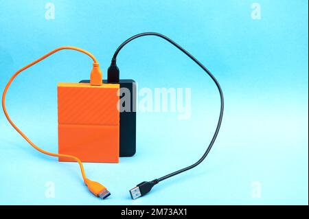 Two external portable hard disk drives isolated on light blue ...