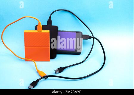 Three external portable hard disk drives isolated on light blue ...