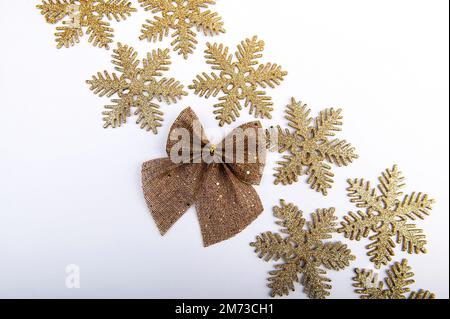 Burlap bow with gold glitter and snowflakes on white background ...