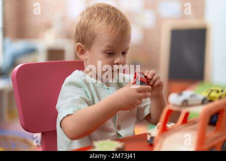 Adorable toddler playing with car toy sitting on table at kindergarten ...
