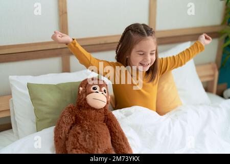 Adorable hispanic girl waking up stretching arms at bedroom Stock Photo ...