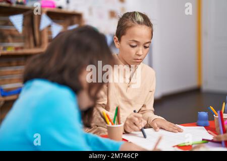 Adorable toddler student drawing on notebook sitting on table at ...
