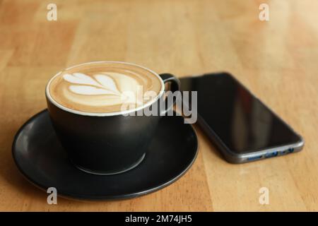 a cup of late coffee with flower shape design on top at cafe Stock ...