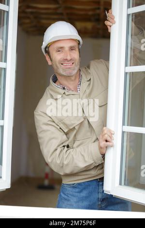 happy construction worker installing window in house Stock Photo - Alamy