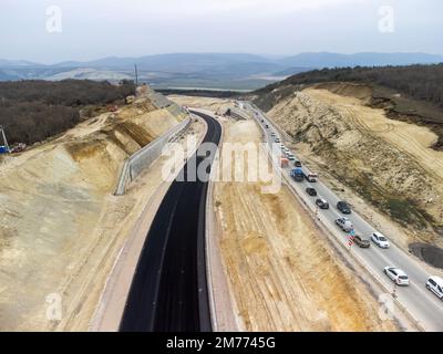 Mountain road constraction. Workers reinforce the slope over the new ...
