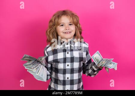 Child with lots of money dollar banknotes isolated over yellow studio ...