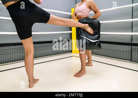 Athlete practicing low kick with her partner in the ring at a ...