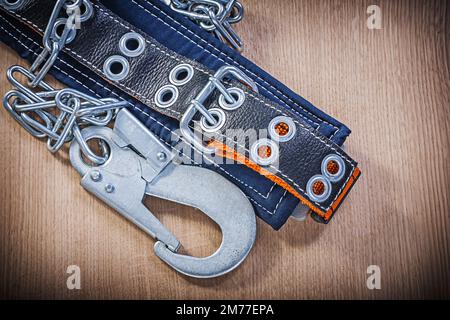 Construction body belt with metal carabiners chain hard hat on wooden ...