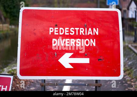 Bright red pedestrian diversion sign with white arrow Stock Photo - Alamy