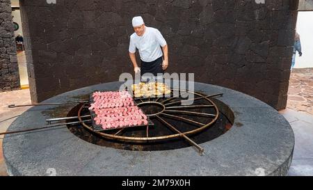 Barbecue over earth hole, chicken thighs, sausages, barbecue with earth ...