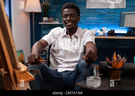 Smiling artist with chronic degenerative disease in art studio. African ...