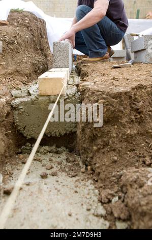 Laying a new wall in a freshly landscaped garden, firstly with a layer ...
