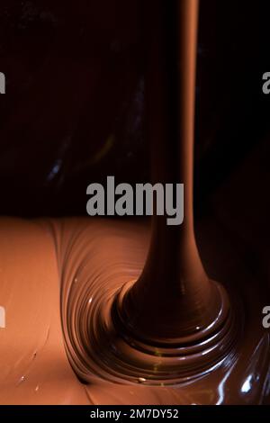 Liquid chocolate pouring into vats and tubes from pipes at a choclate ...