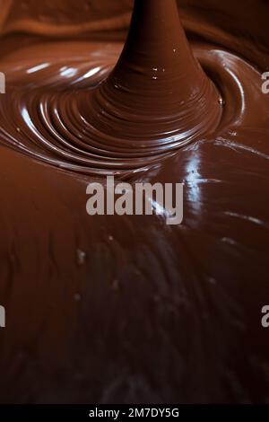 Liquid chocolate pouring into vats and tubes from pipes at a choclate ...