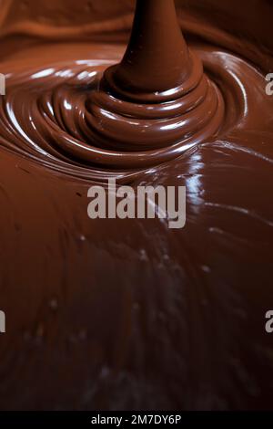 Liquid chocolate pouring into vats and tubes from pipes at a choclate ...