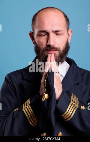 Airline pilot in uniform praying to gods, looking upwards, standing ...