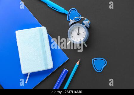 Set of blue stationery with notebooks and alarm clock on dark ...